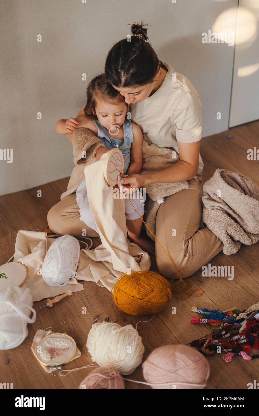 The mother teaching the little girl how to make a composition on a ...
