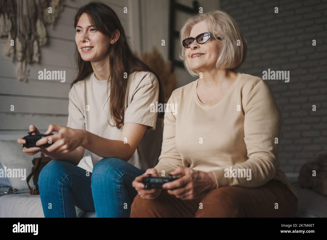 Portrait of a mother and her adult daughter having fun playing video ...