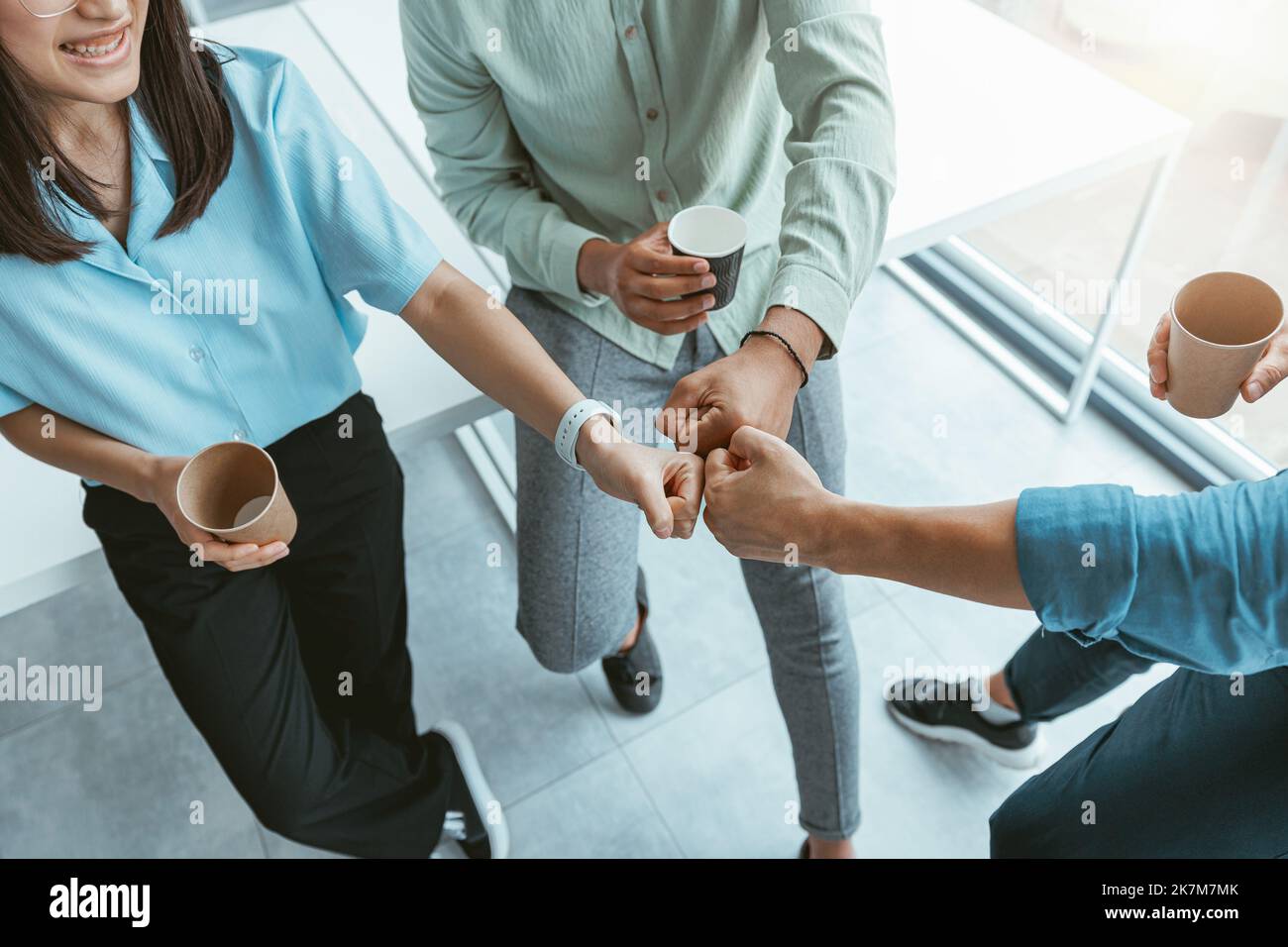 Smiling group of multiethnic colleagues drinking coffee and talking ...