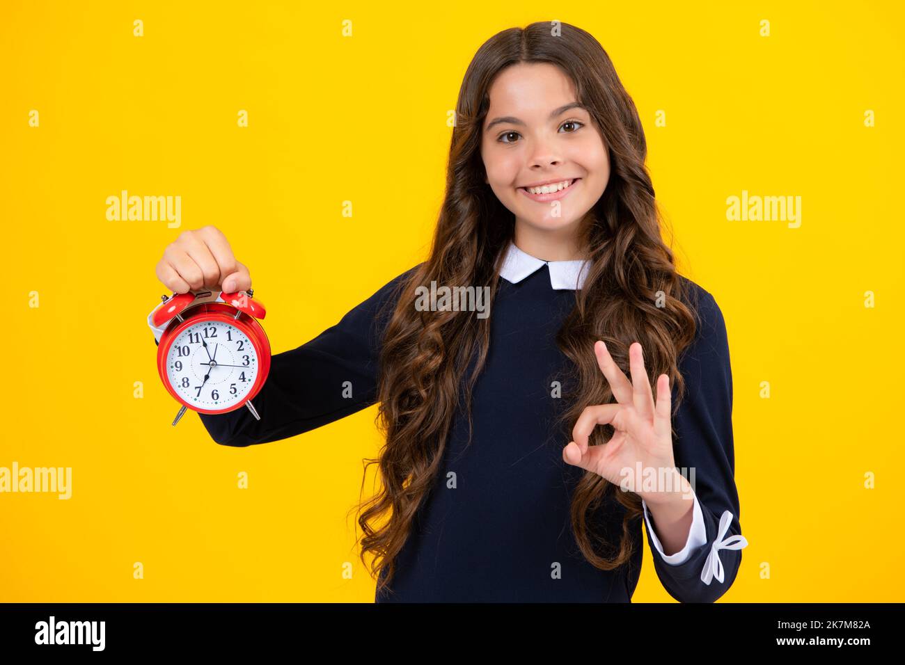 Punctual teen girl checking time. Child with alarm clock showing time ...