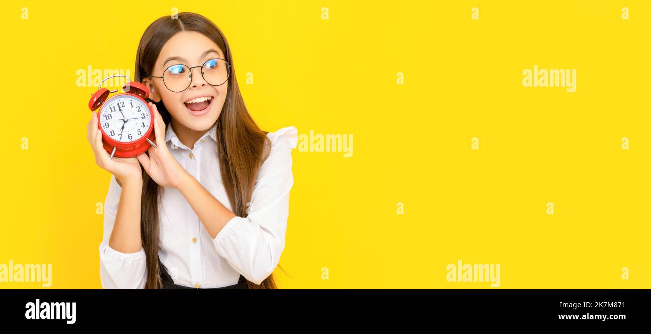 amazed teen girl in school uniform and glasses listen alarm clock ...