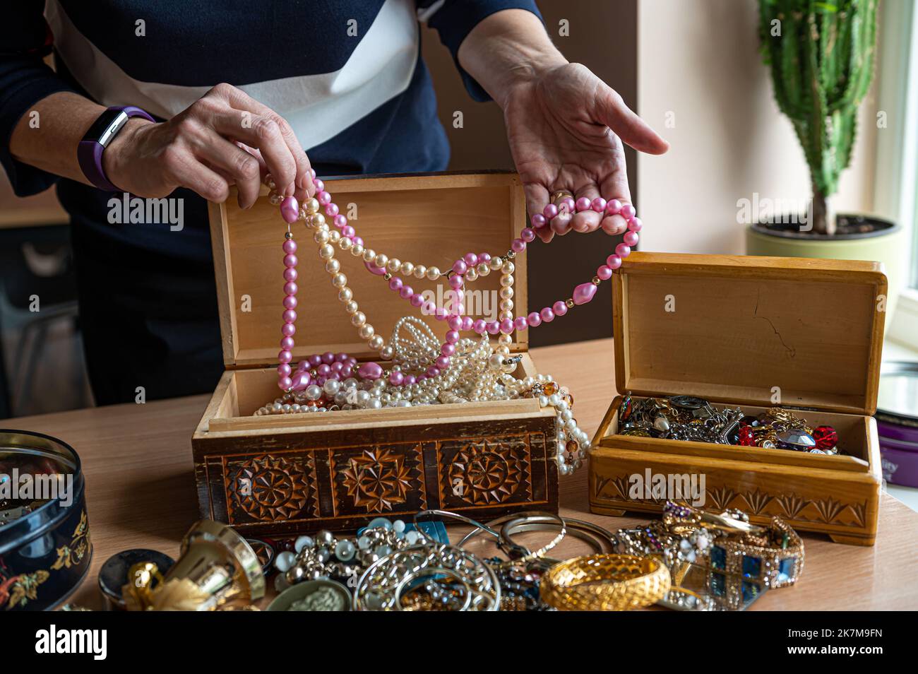 Wooden treasure chest with valuables. A woman holds beads, necklaces ...