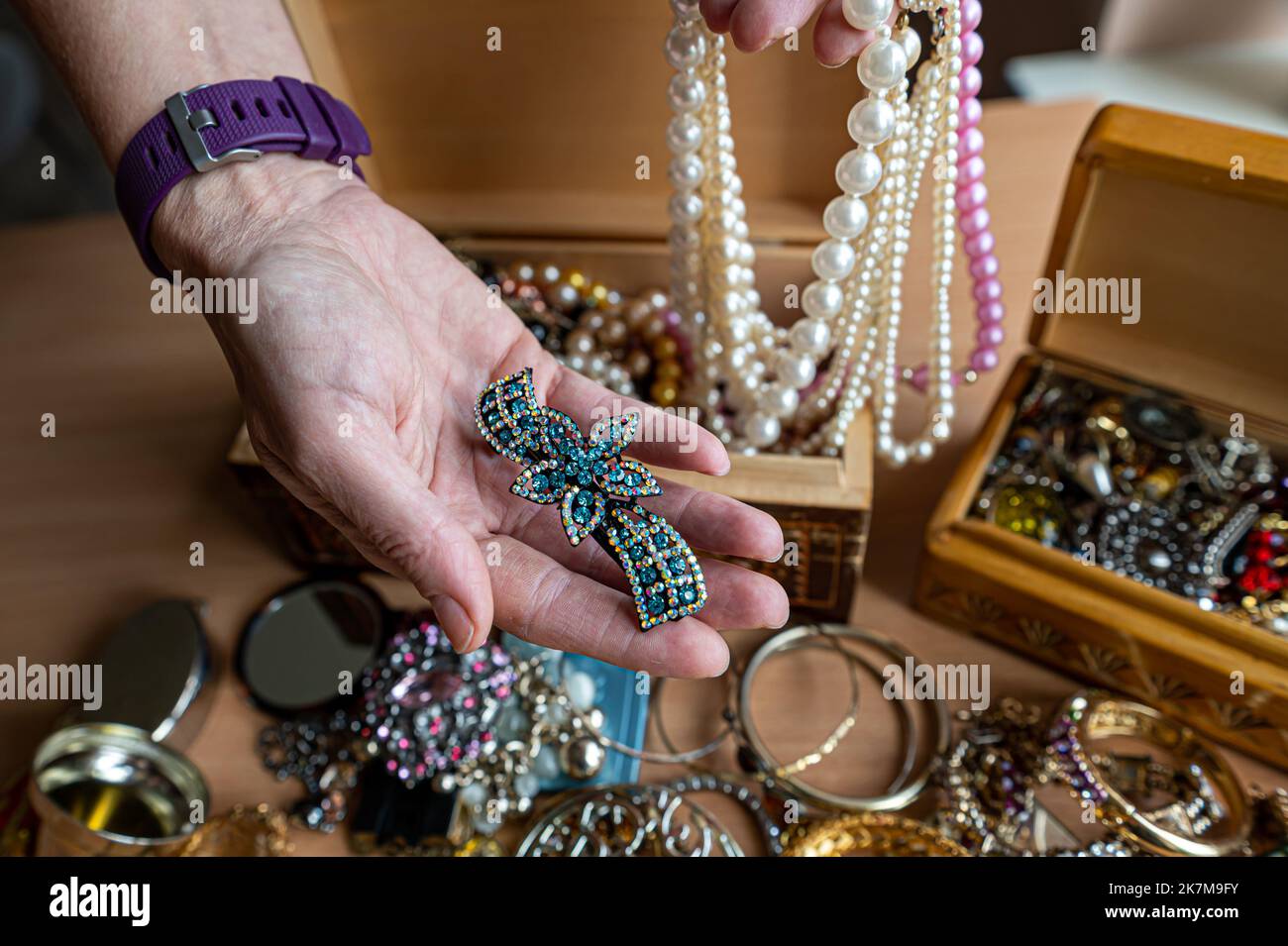 Wooden treasure chest with valuables. A woman holds beads, necklaces ...