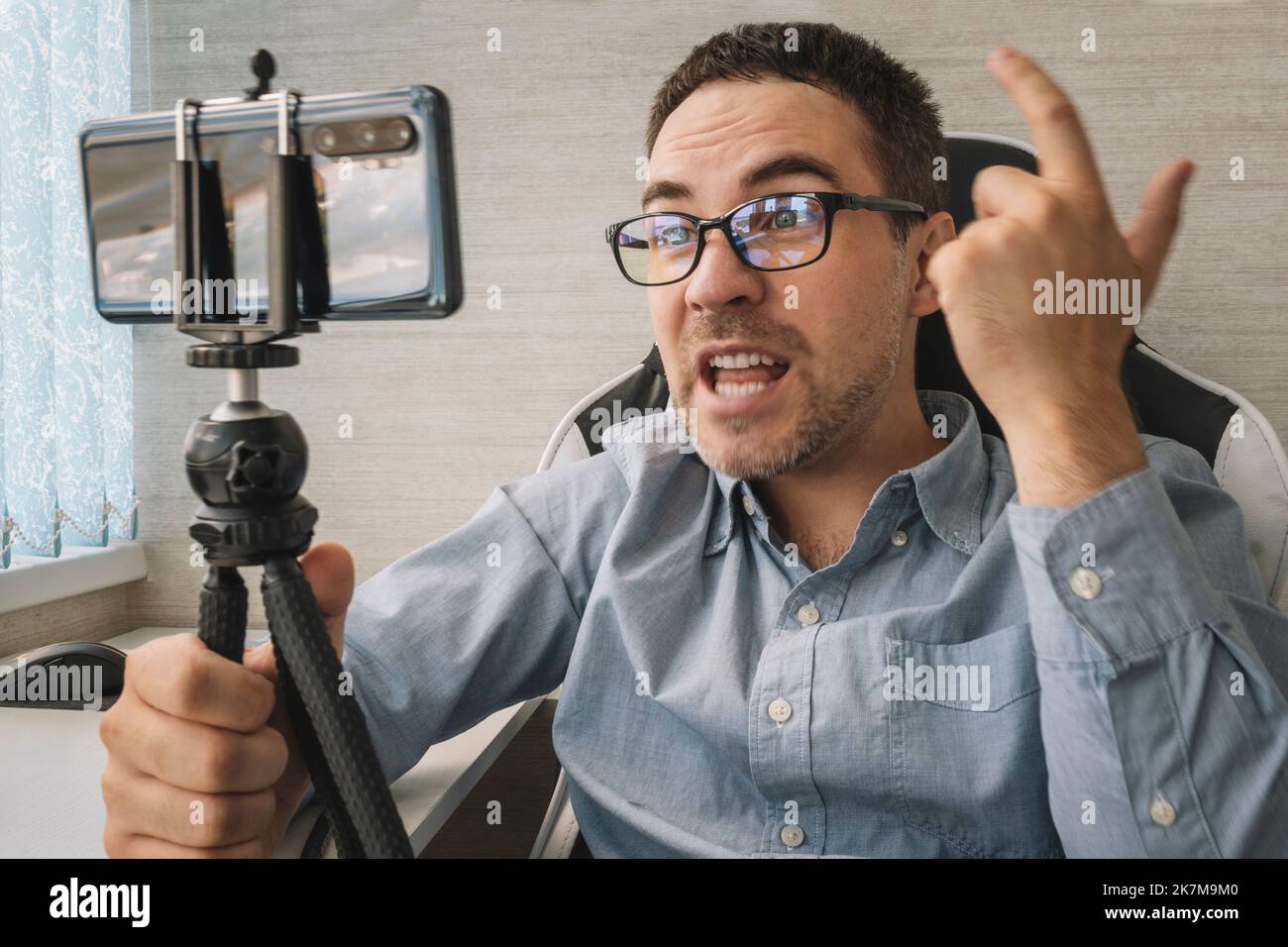 Angry sad upset man in blue wear emotionally talking on mobile phone ...