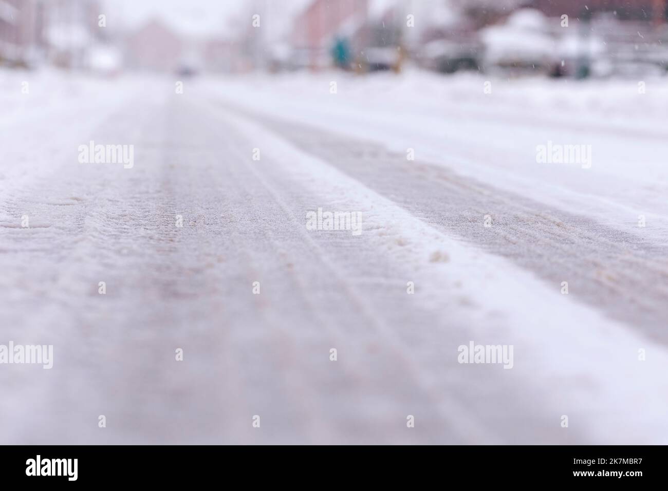 A low portrait of an asphalt road or street covered in snow and ice ...