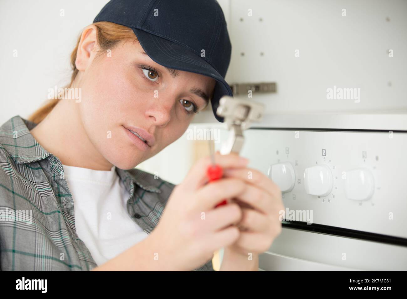 woman holding hinge to fit on kitchen cupboard Stock Photo - Alamy