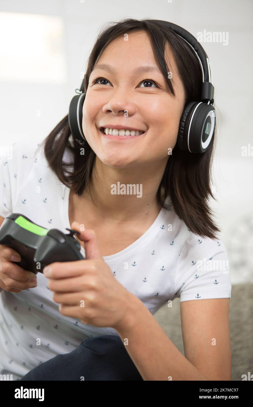 female gamer wearing headphones using a wireless controller Stock Photo ...