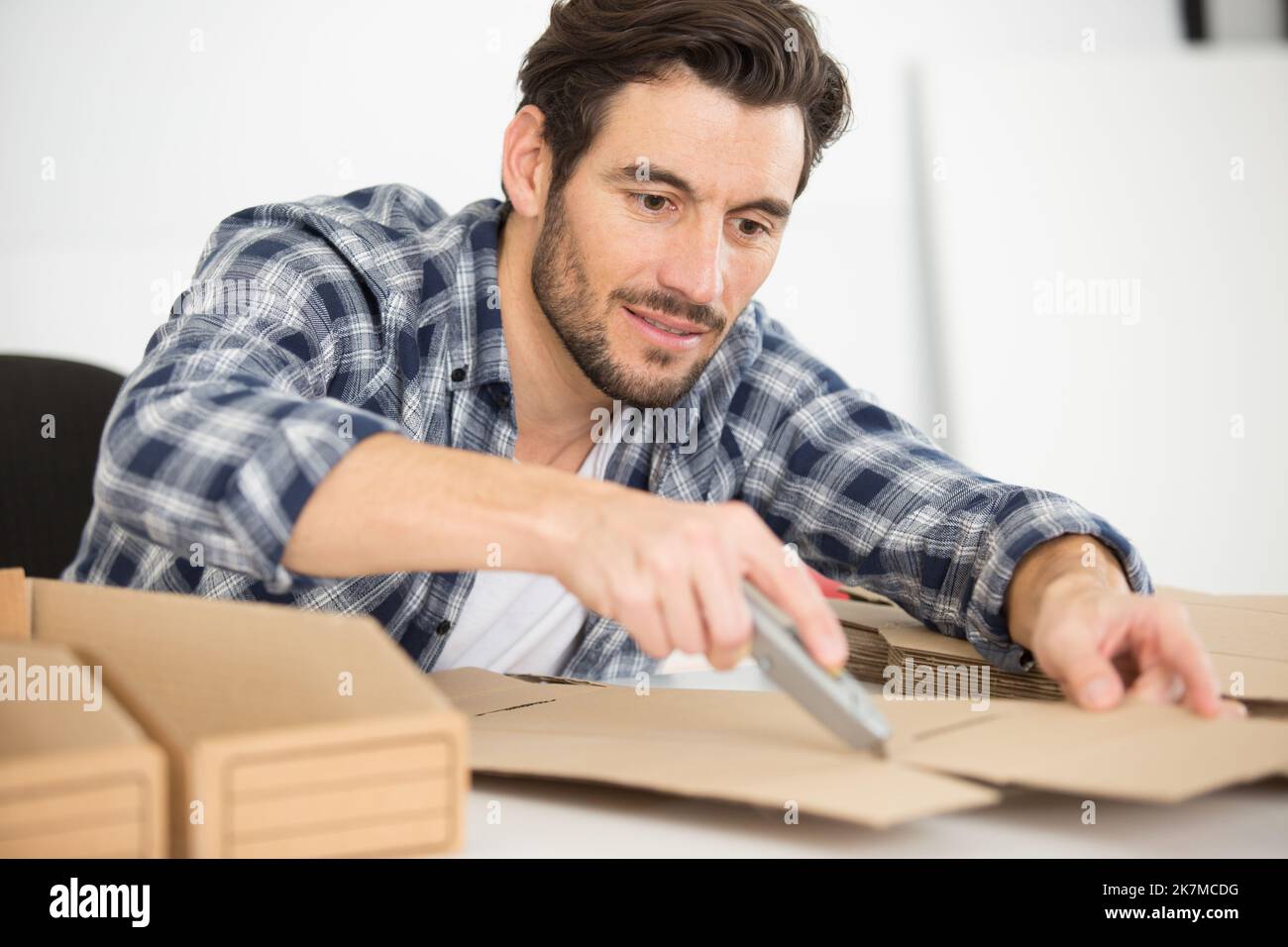 man running knife along fold in cardboard box Stock Photo - Alamy