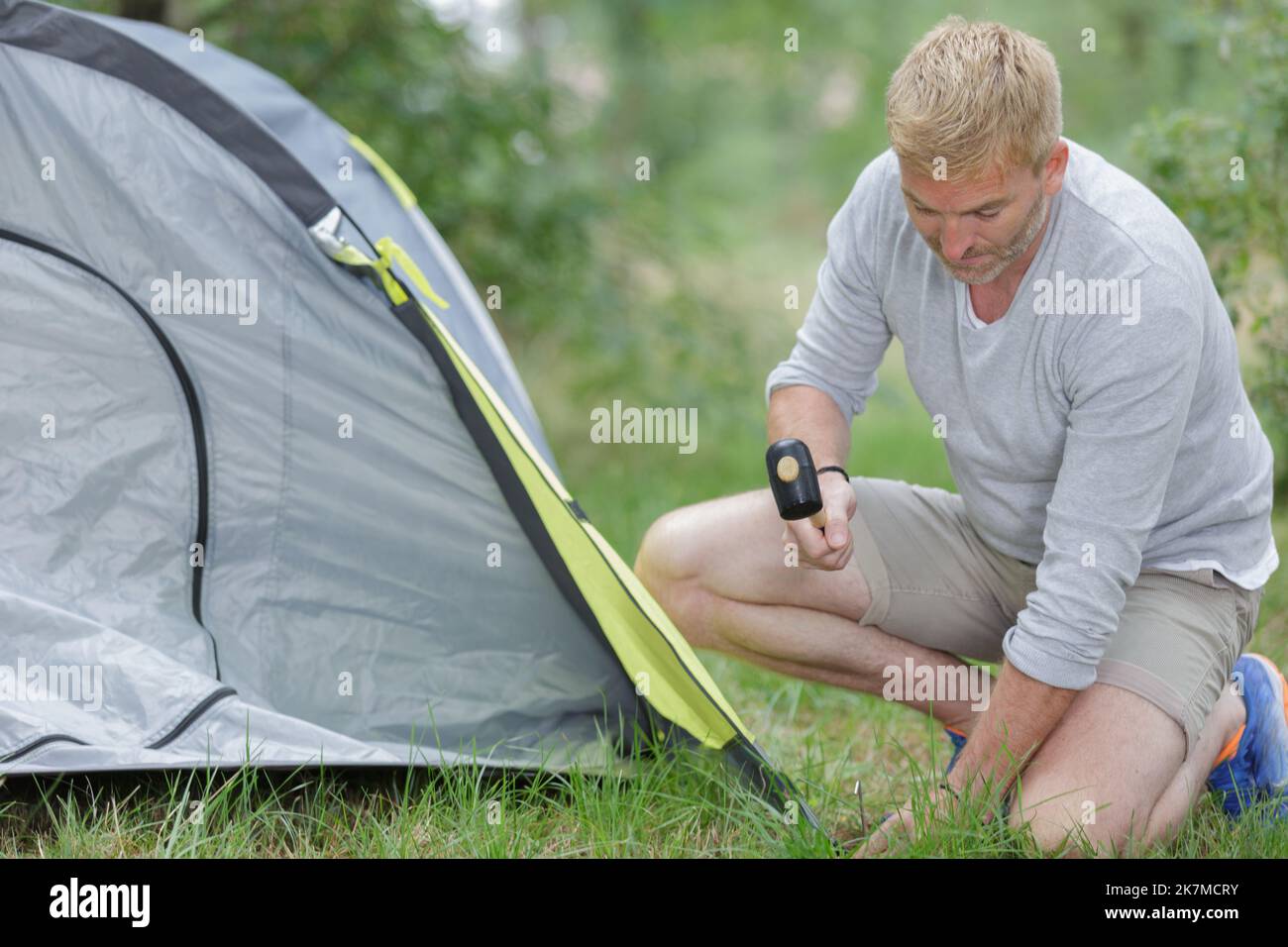man with hammer setting up the tent at camp ground Stock Photo - Alamy