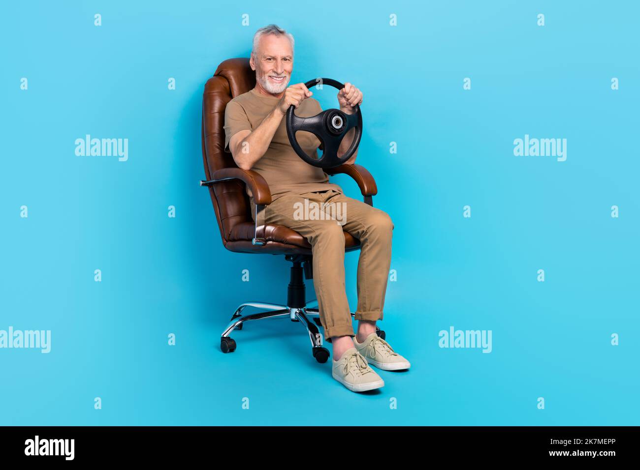 Full body portrait of positive man sit chair hands hold wheel isolated ...