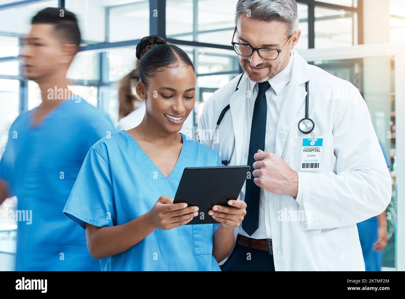 Diversity, doctor and nurse on a tablet planning a surgery strategy or talking about medical ...