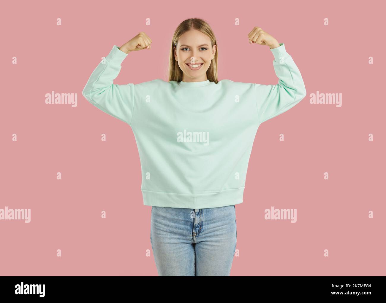 Cheerful beautiful woman smiling and showing her muscles funny to show ...