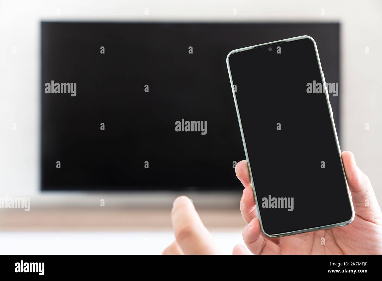 Young adult man hand tap on white screen smartphone with screen tv on ...