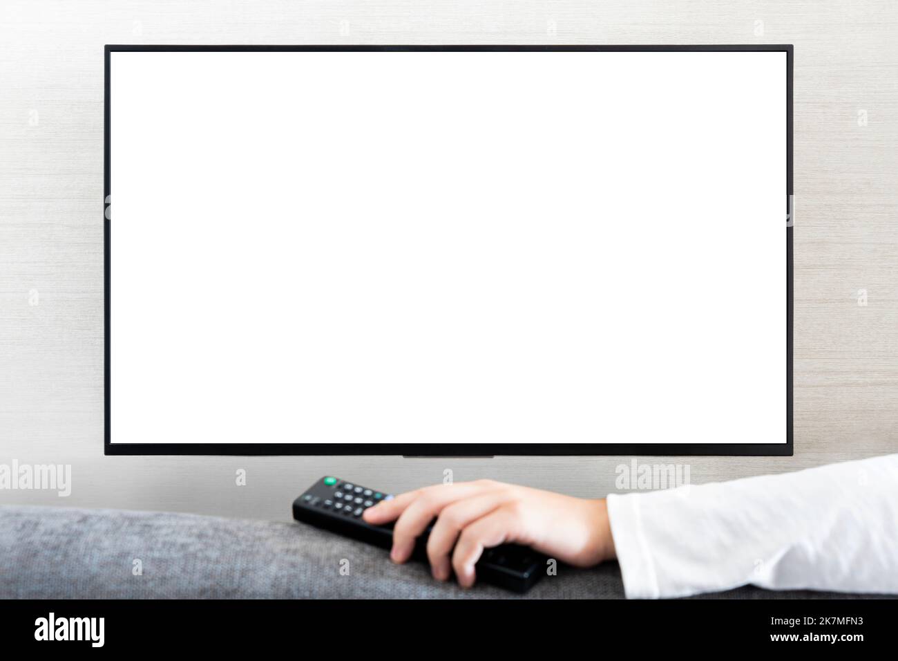 TV remote control in male hand in front of widescreen TV set with blank ...