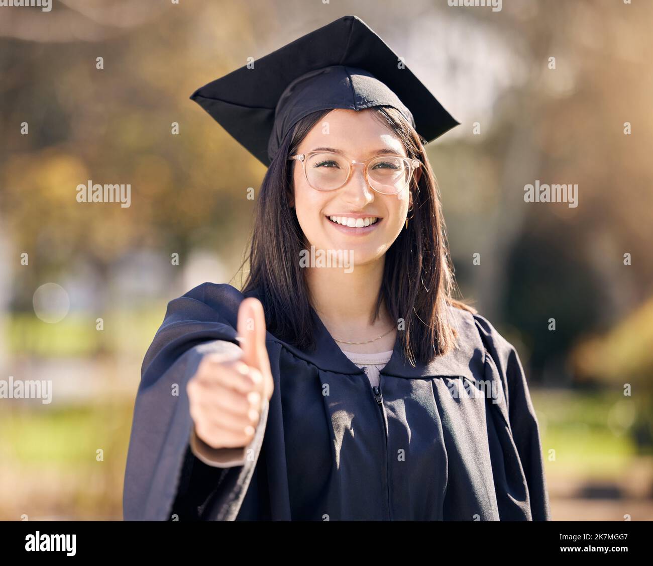 Well done on what youve achieved. a young woman showing thumbs up on graduation day Stock Photo ...