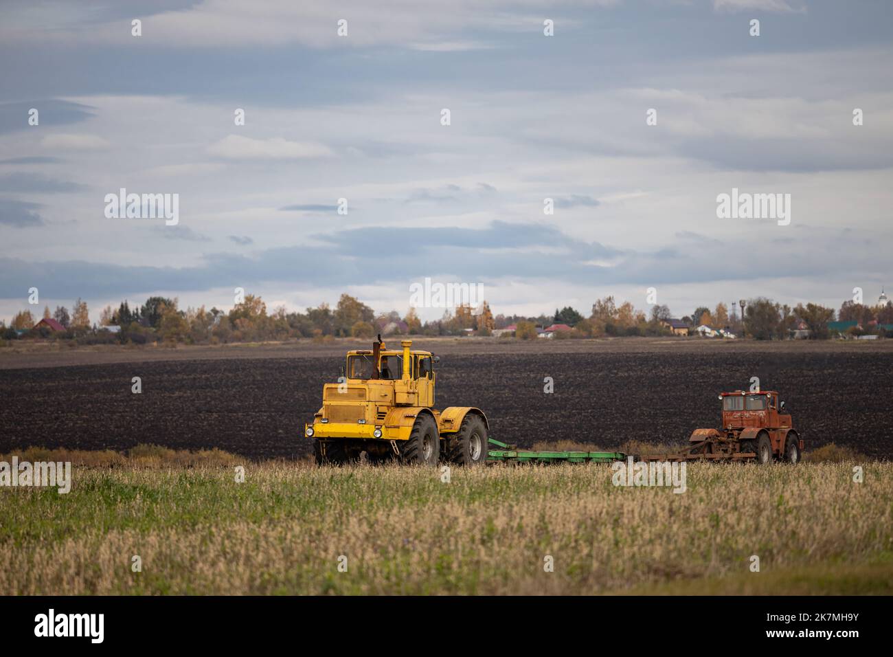 old model tractor working in the field. two tractors work together ...