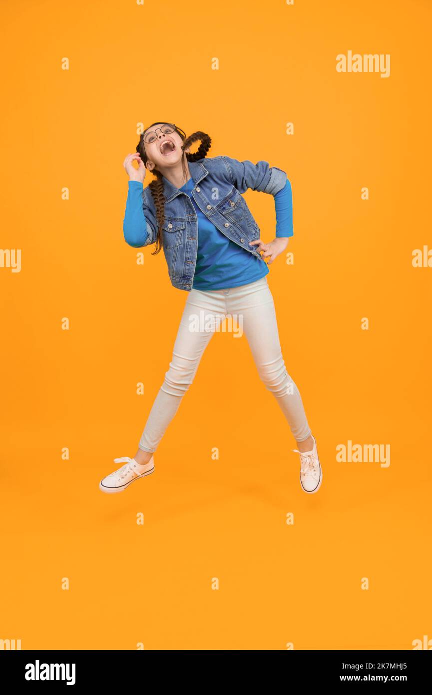 jumping smiling kid girl with stylish braided hair wearing eyeglasses ...