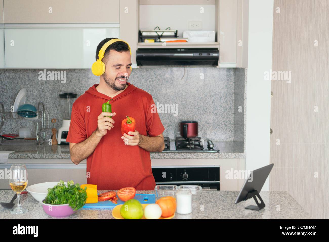 man cooking lunch while doing a video chat with his tablet at modern ...