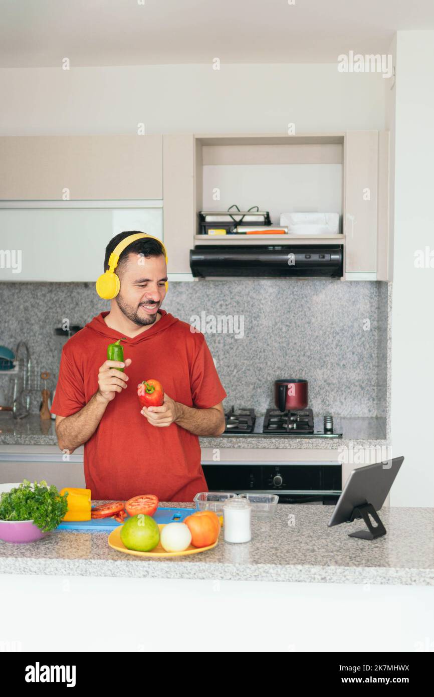 man at kitchen preparing a recipe following the steps looking at his ...