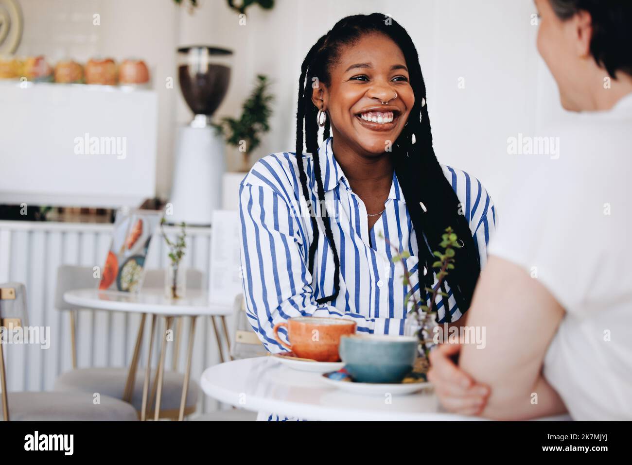 Happy young businesswoman smiling while having a coffee meeting with a ...