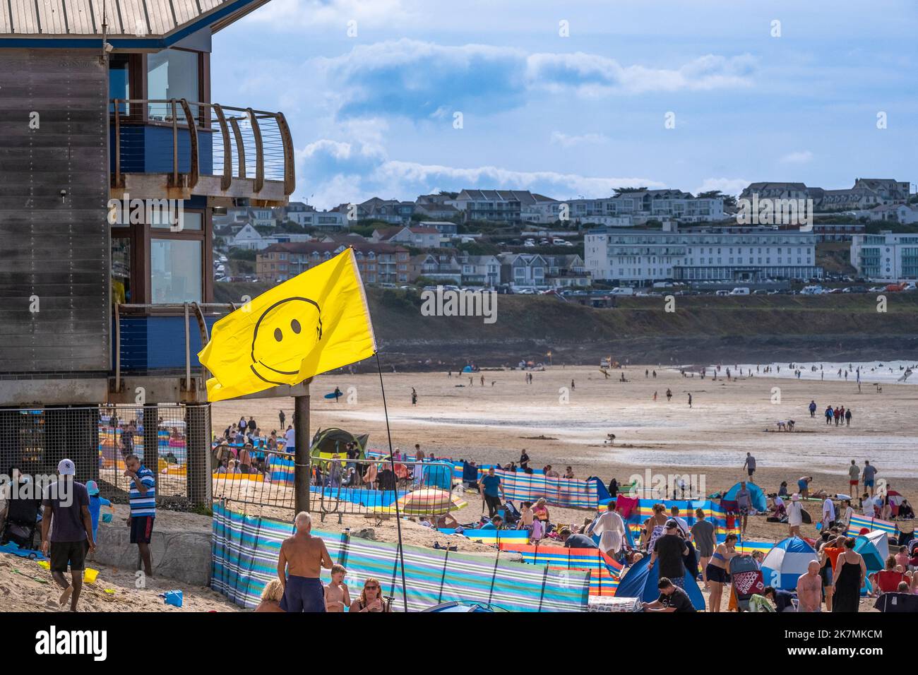 A flag with a smiley face symbol fluttering on a busy crowded Fistral ...