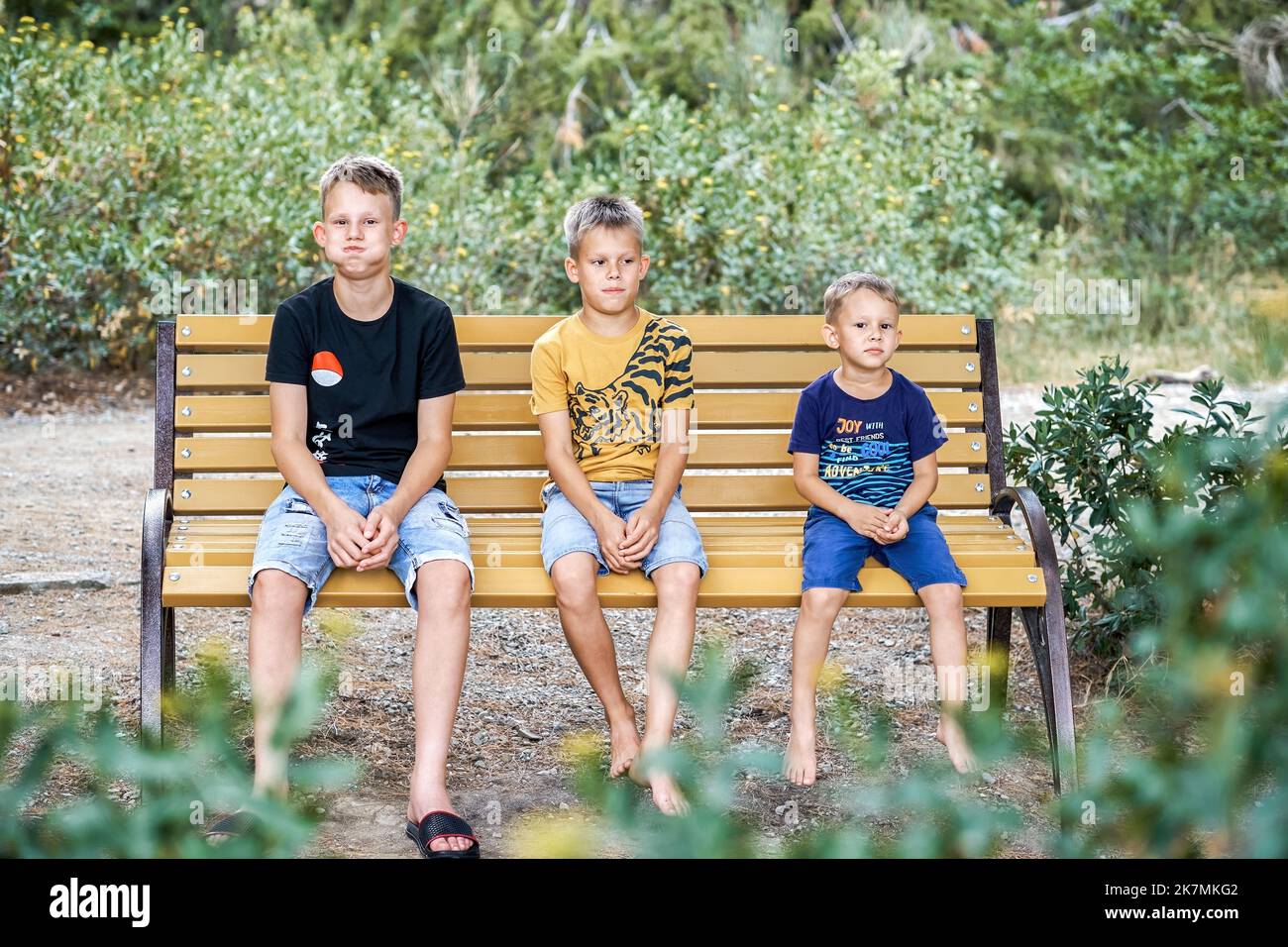 Joyful brothers sit on bench tired from long walk in park. Fair-haired ...