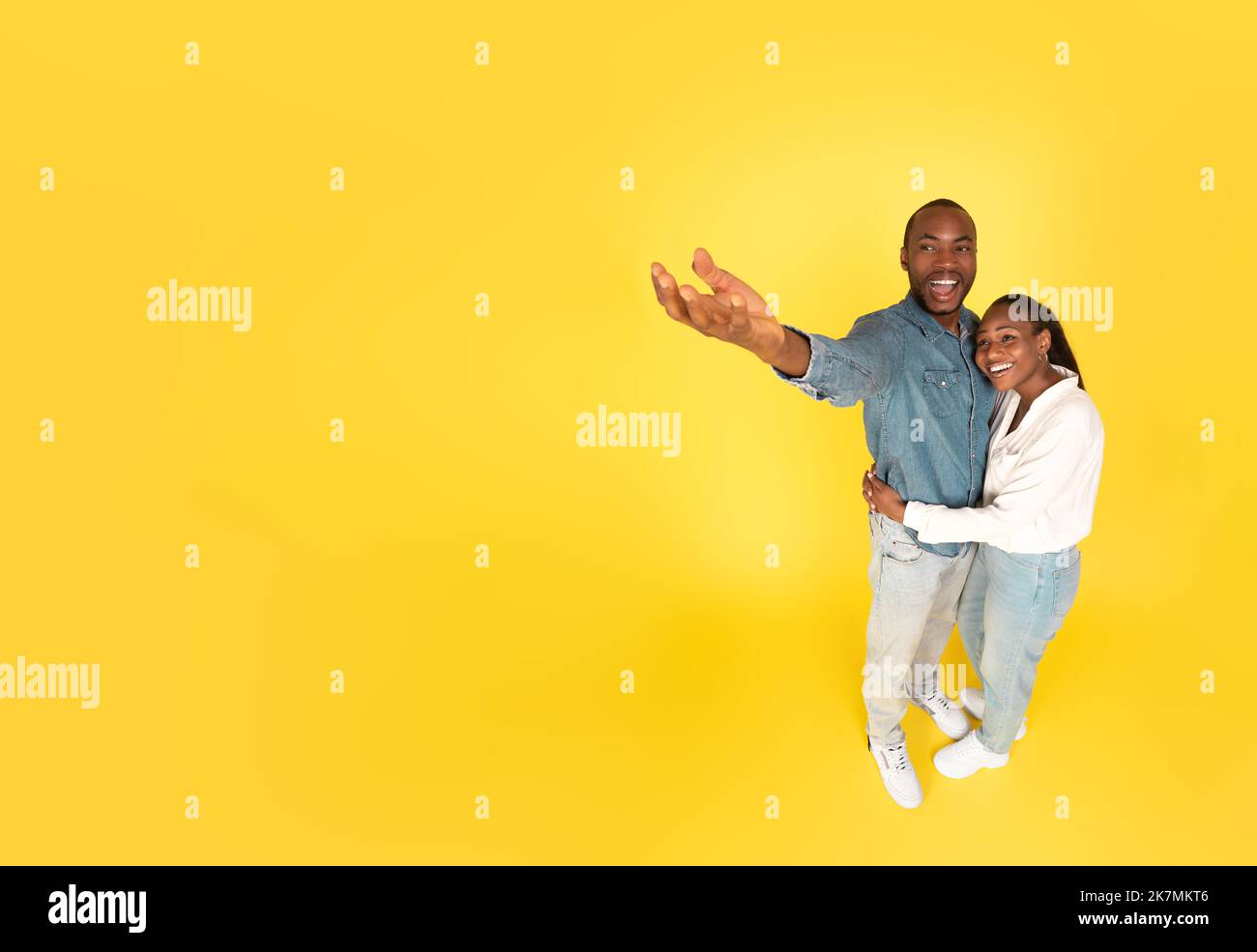Black Couple Showing Invisible Object To Camera Over Yellow Background ...