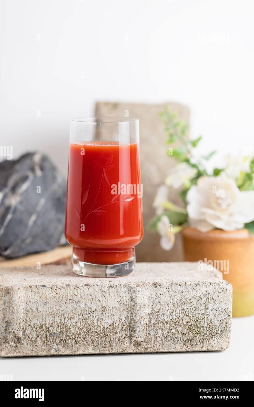 tomato juice in clear glass on white with rocks background. Close-up ...