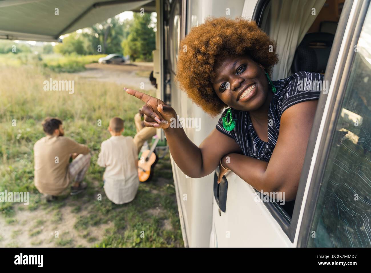 Positive Black female owner of traveling camper looking out of the ...