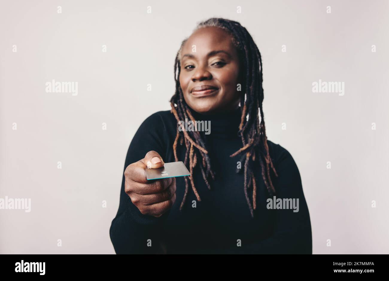 Paying with a credit card. Mature woman with dreadlocks holding out a ...