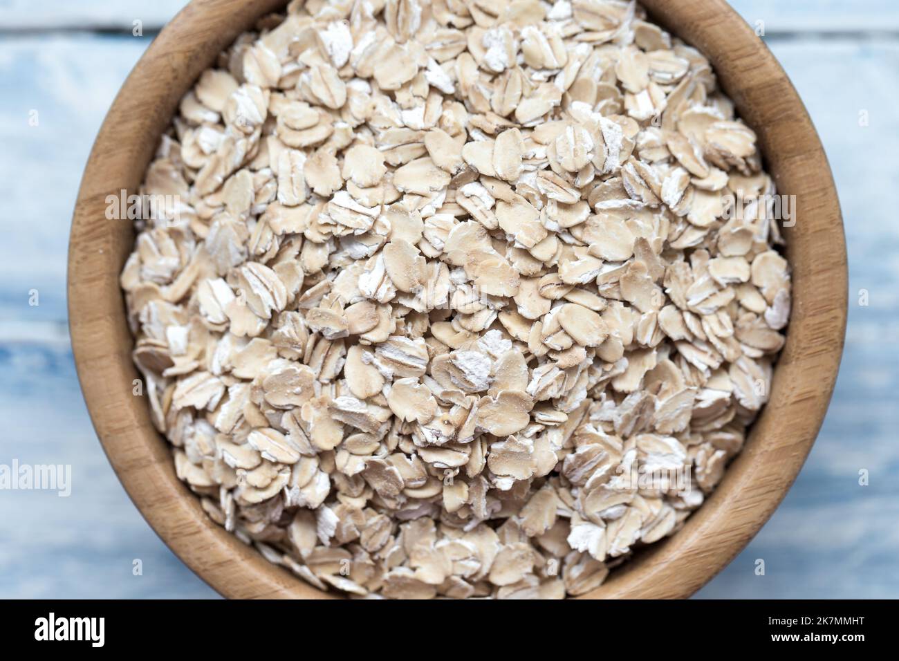Oat flakes uncooked in wooden bowl on blue background. Ingredient for ...