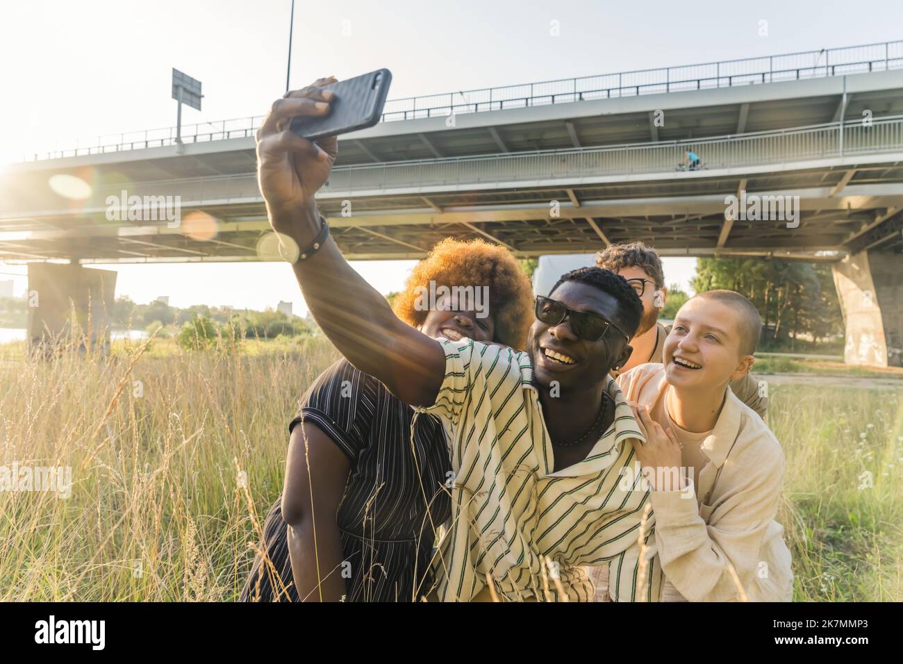 Selfie taken outdoors. Interracial group of four people - two casually ...