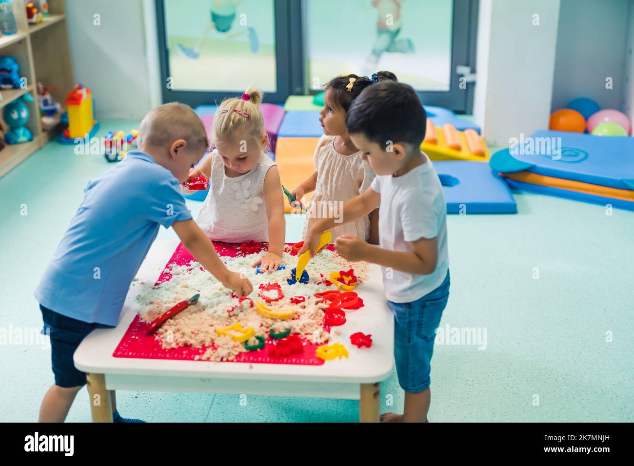 four kids standing at the little table and putting figures in the ...