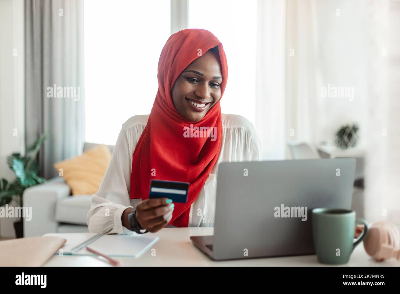 Cashless payment. Happy black muslim woman in hijab holding credit card ...