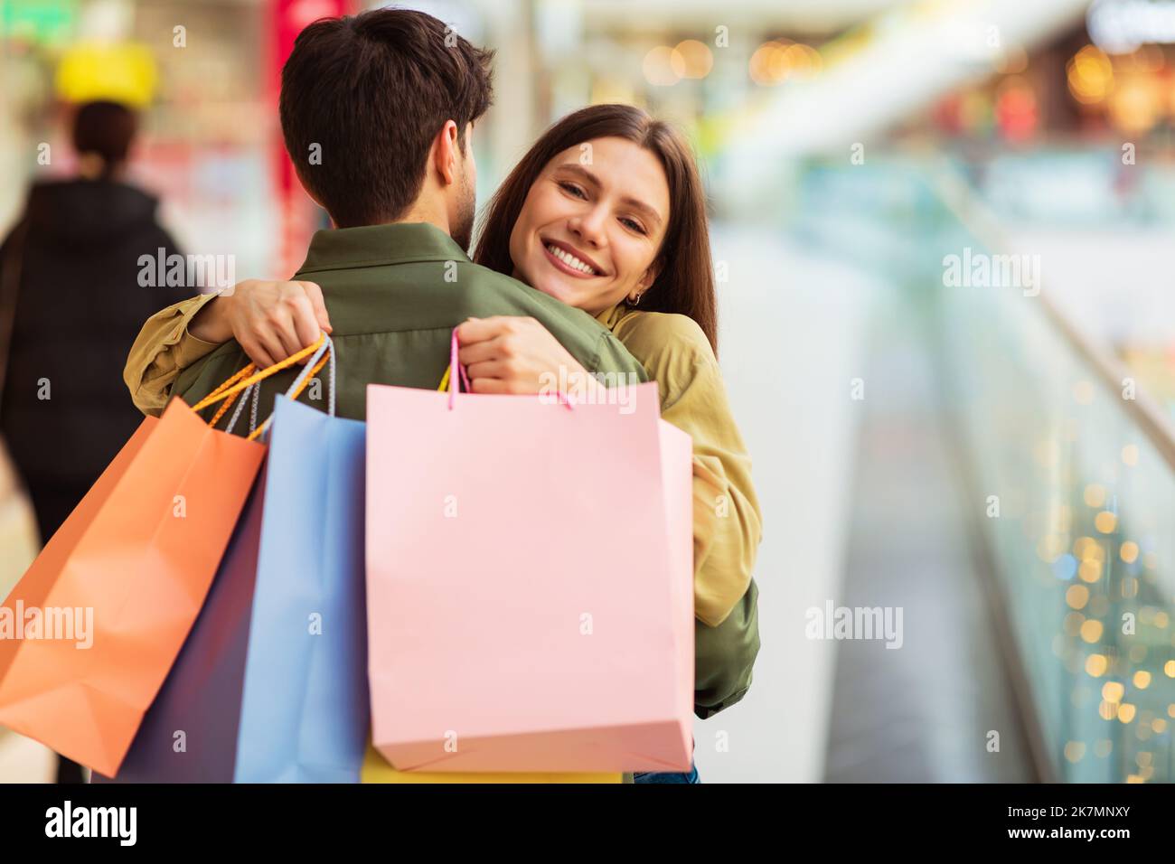 Female Buyer Hugging Husband Holding Bags Shopping In Mall Indoors ...