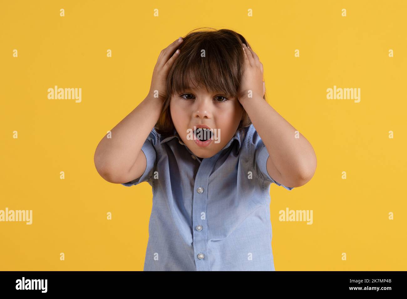 Oh no. Cute little boy having some troubles, touching his head with ...