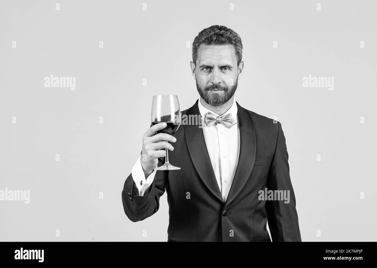 handsome tuxedo man cheers with glass of red wine hold gift box behind ...