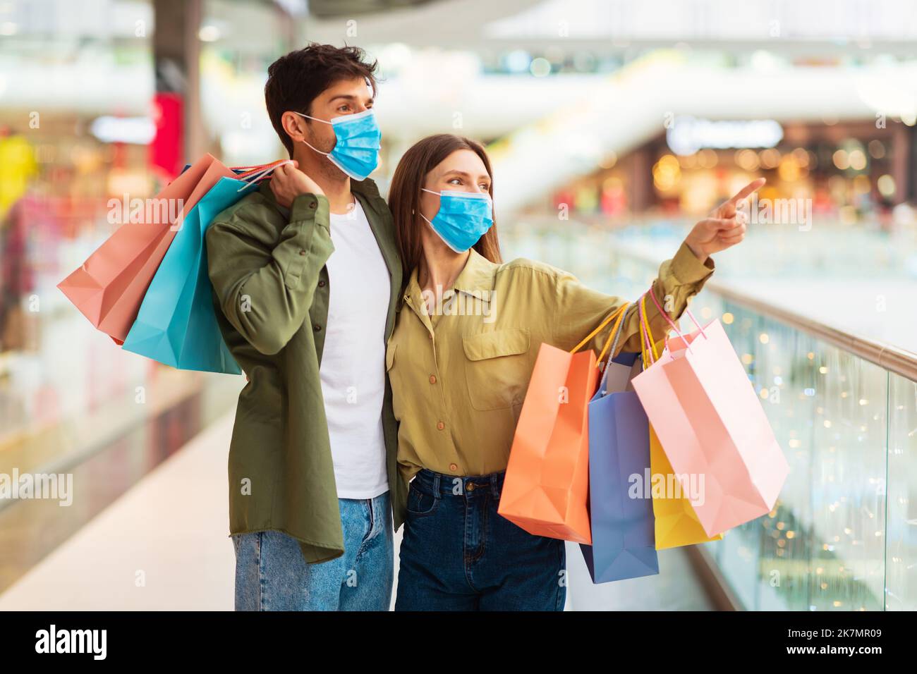 Buyers Couple Doing Shopping Pointing Finger Aside Posing In Mall Stock ...