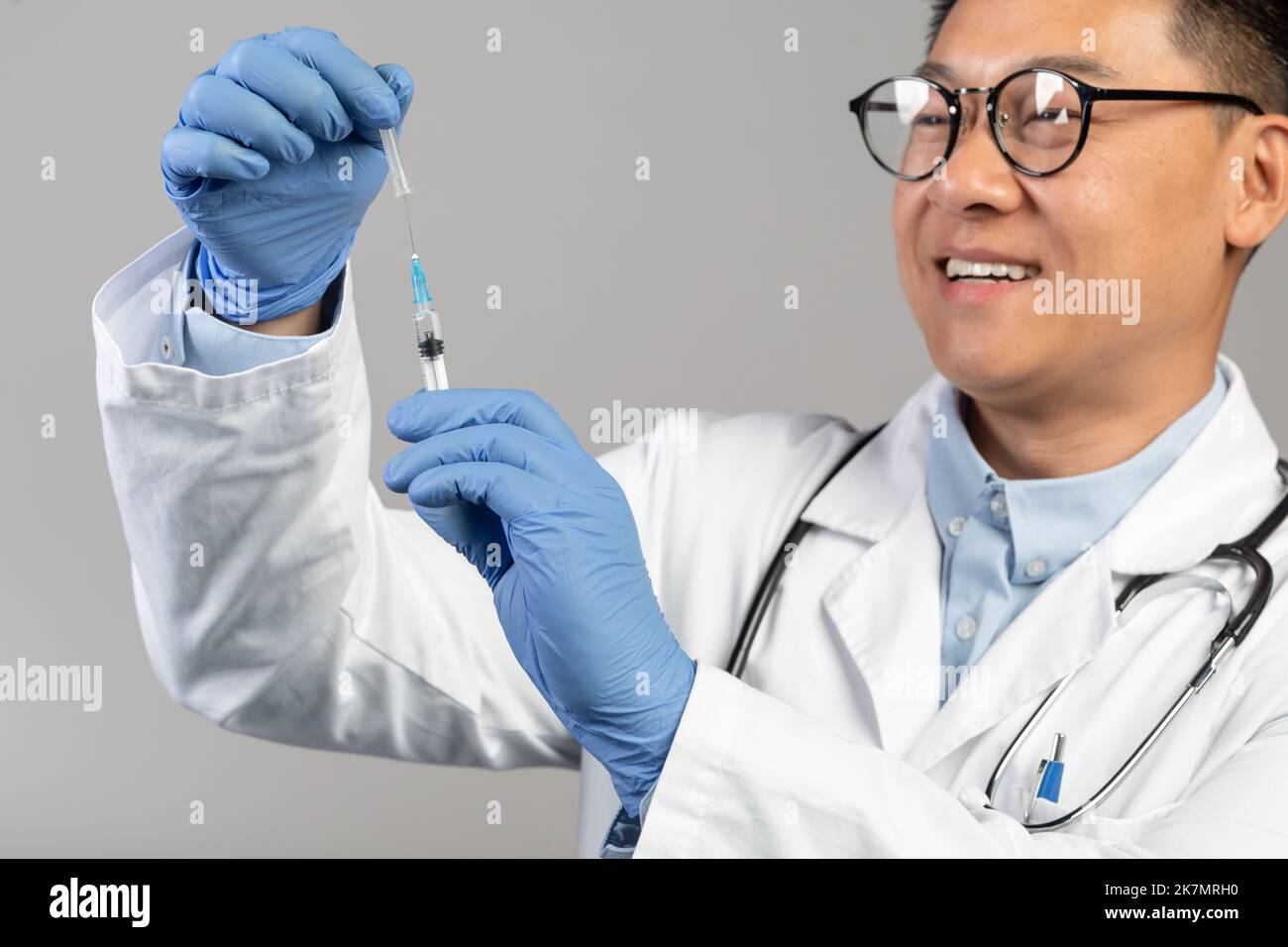 Smiling middle aged chinese male doctor in white coat and glasses take ...