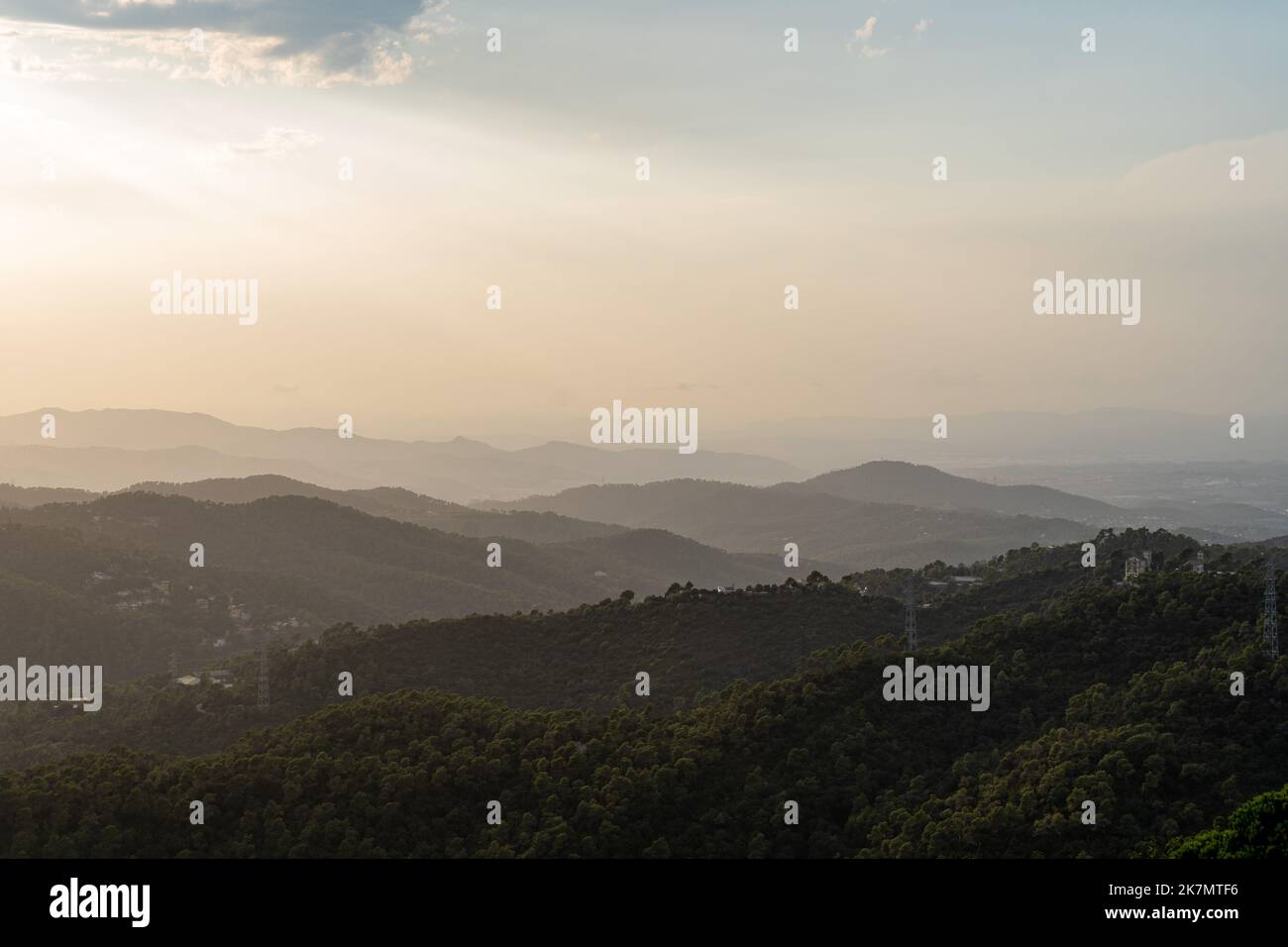 A scenic shot of mountain silhouettes covered in thin fog during the ...