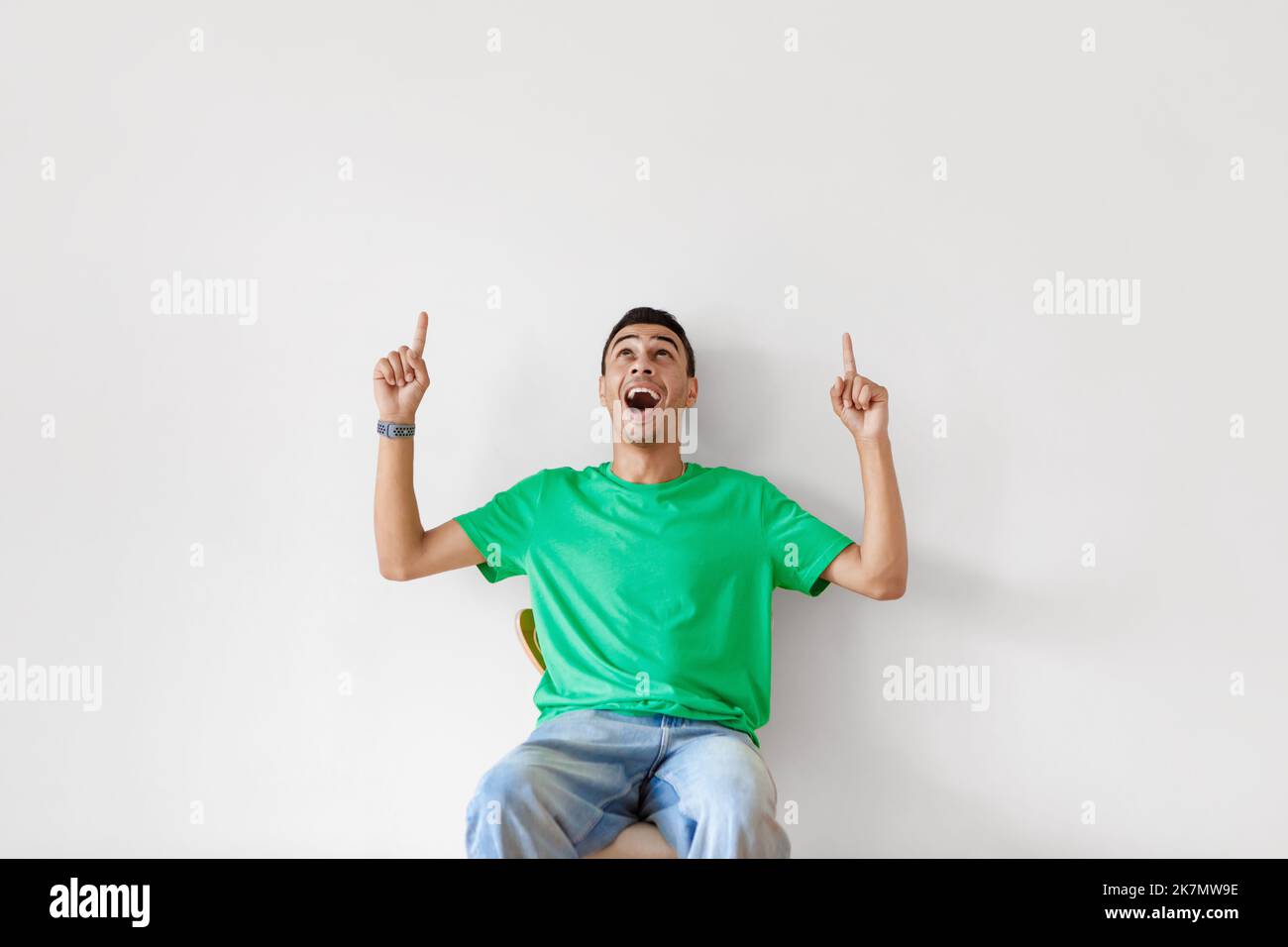 Excited arab man pointing and looking up at copy space, opening mouth ...