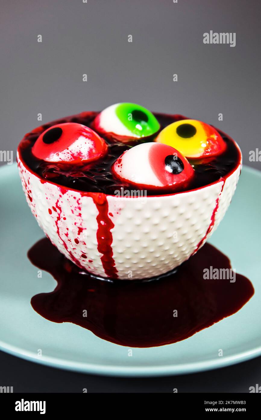 A close up of a bowl full of eyeballs and dripping blood sticky candies ...