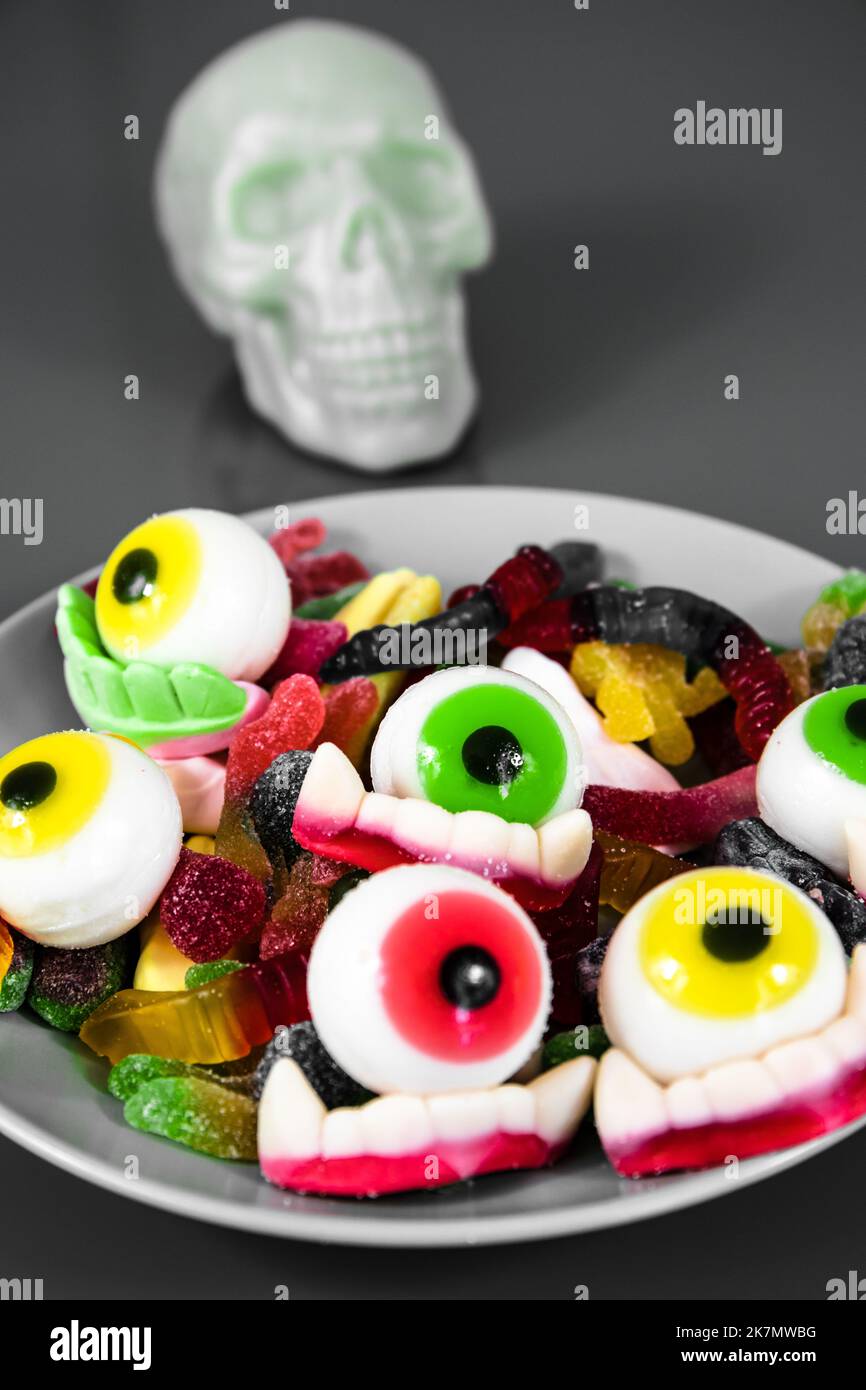 A close-up of eyeball and fang candies with a skull in the background ...