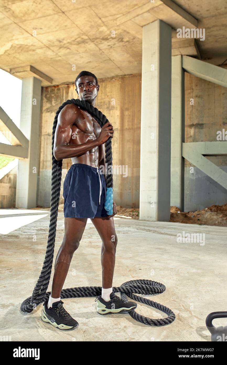 Rope workout. Sport man doing battle ropes exercise outdoor. Black male ...