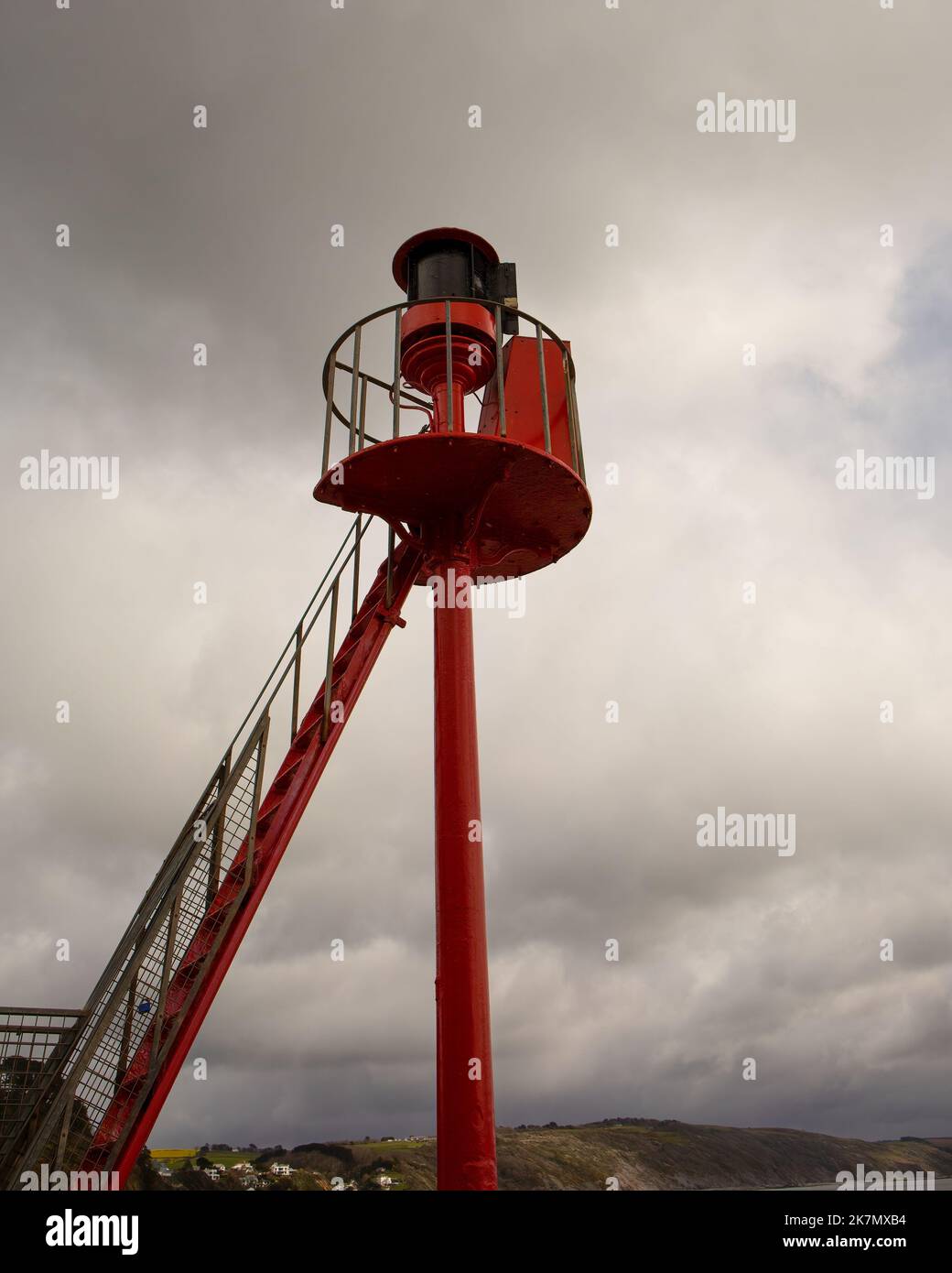 A low-angle vertical shot of a red warning beacon with ladder at harbor ...