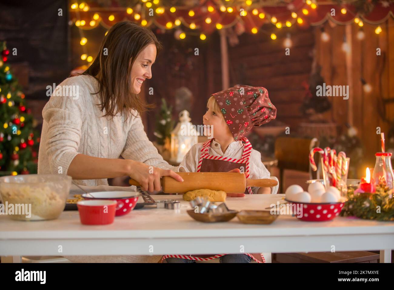 Cute blond child and his mother, baking christmas cookies at home ...