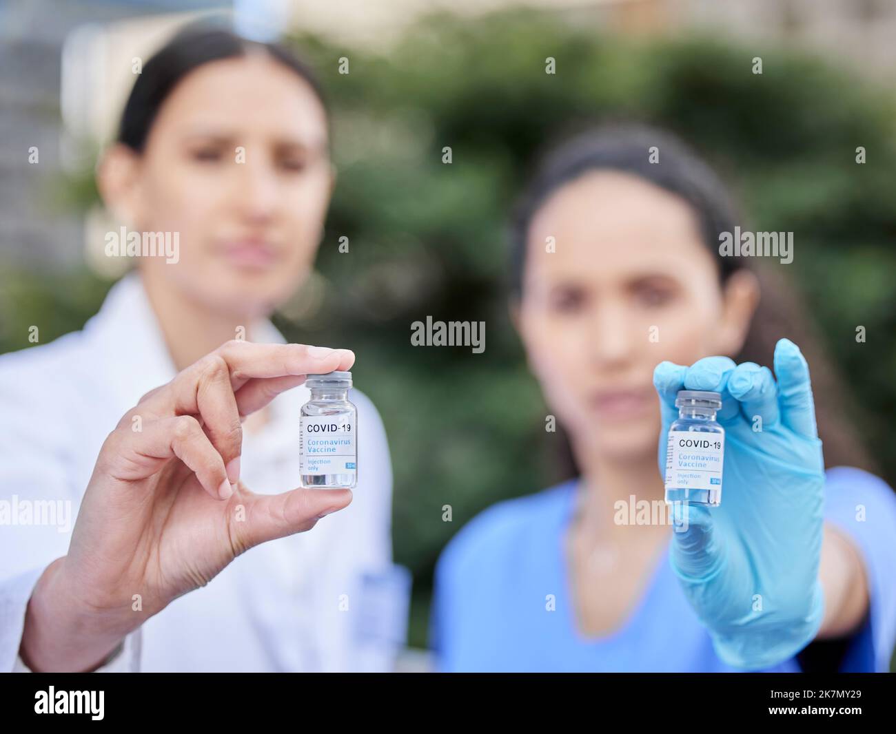 Heres The Solution To Your Problem Two Doctors Holding Vaccine Vials Against A City Background