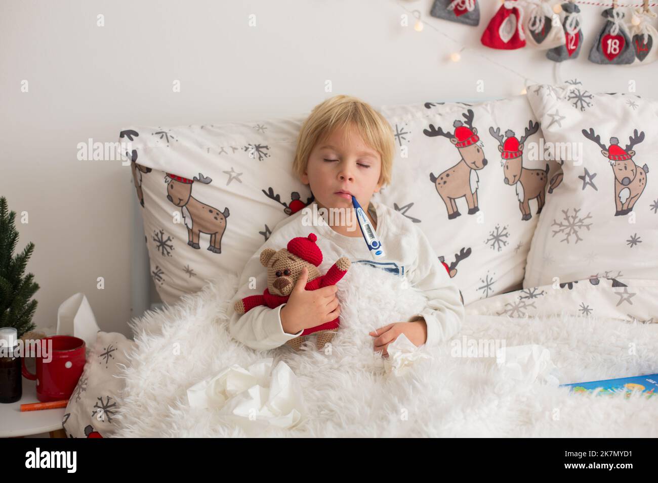 Beautiful blond toddler child, sick boy with fever, lying in bed on ...