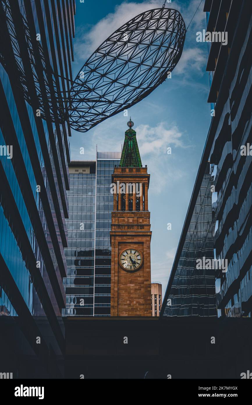 A vertical shot of a Big Ben clock tower through Telstra One Building ...