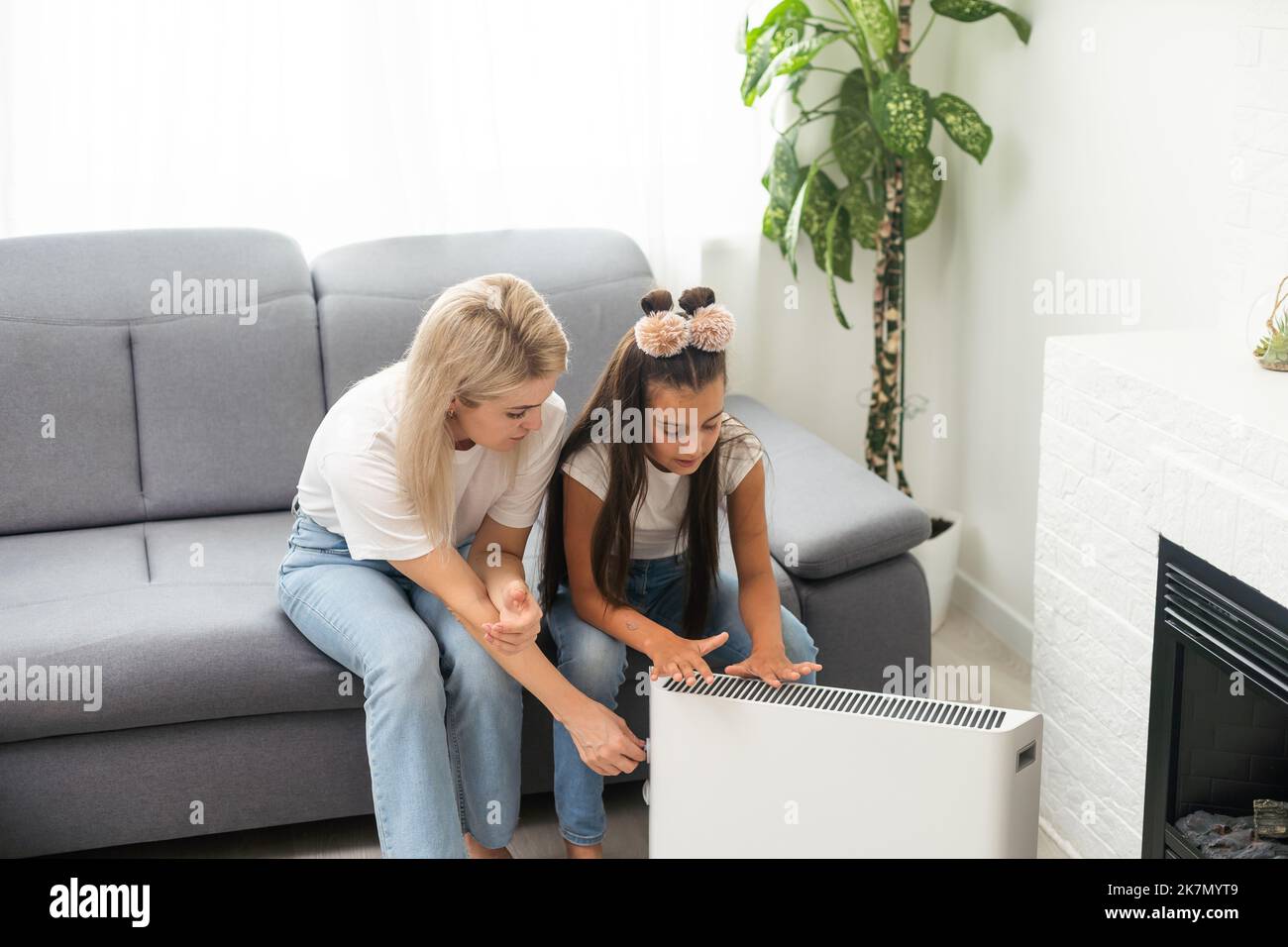 Cold home, freezing family, mother and daughter Sitting Near Heater ...
